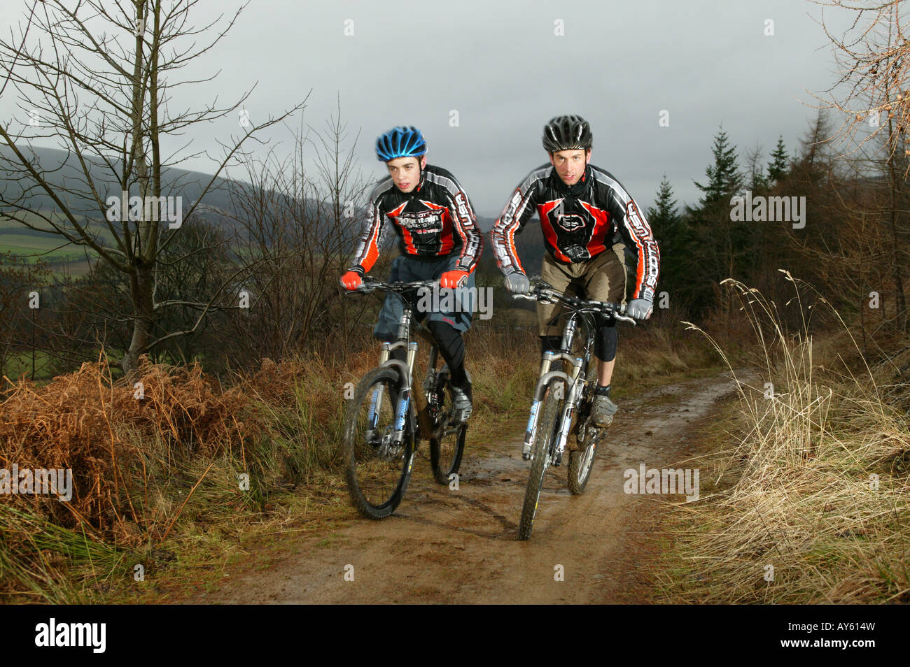 Two cross country mountain bikers ride along a muddy track Stock Photo ...