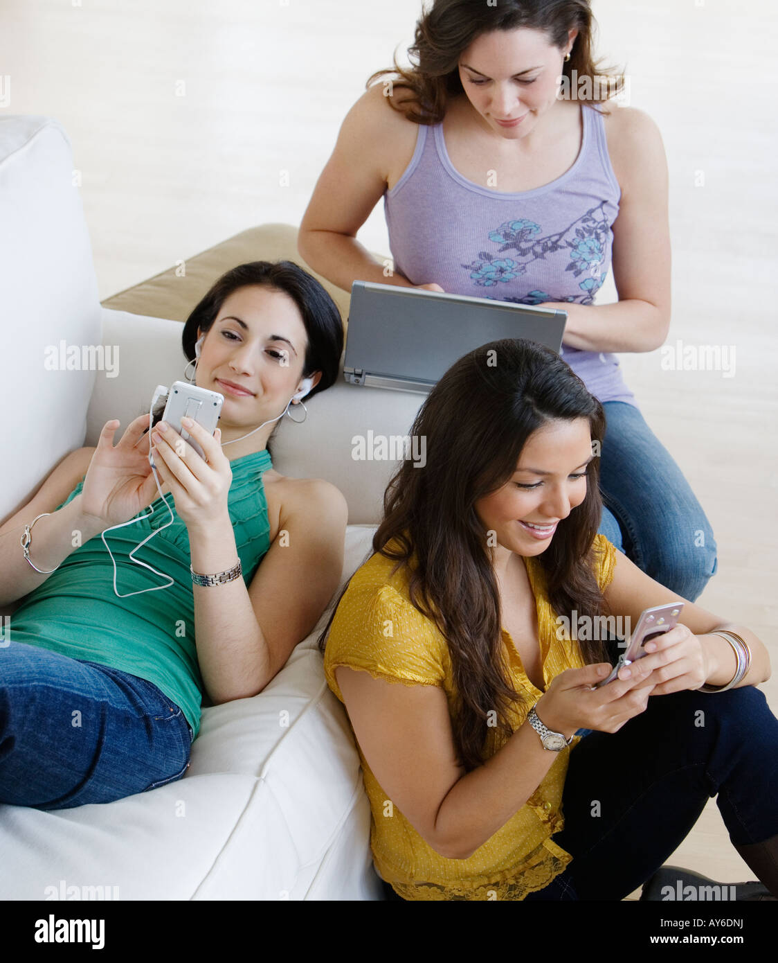 Three young women using wireless devices Stock Photo - Alamy