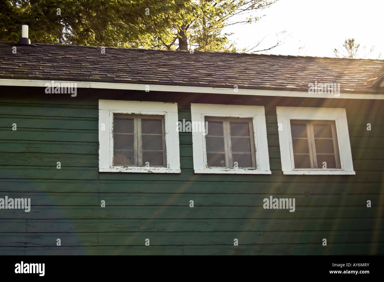 Rays of sunlight shine down on rustic green mountain cabin with 3 white ...