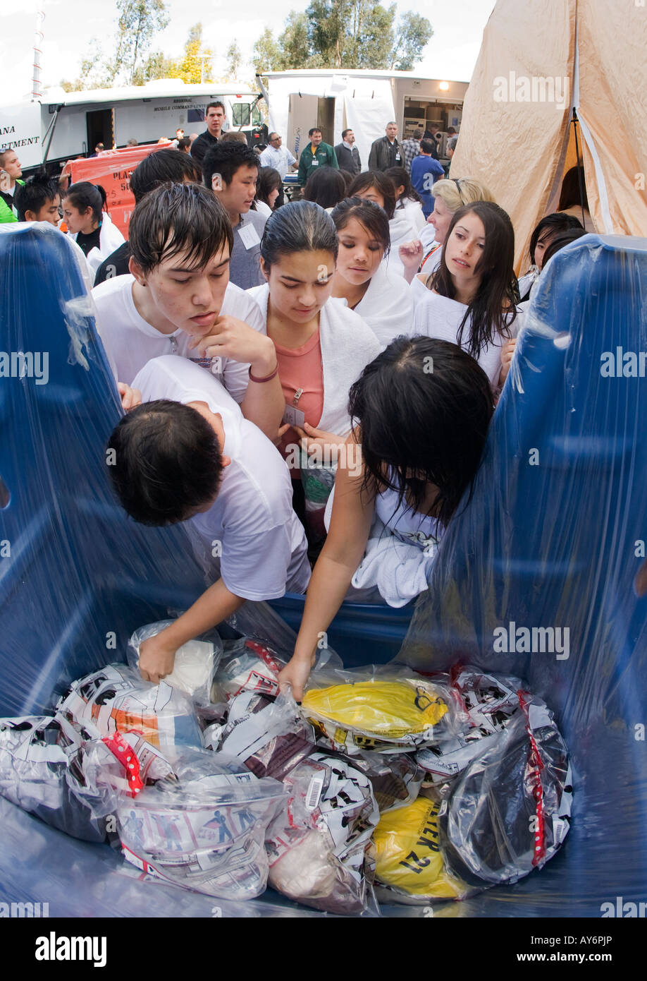 Volunteer victims reach for disposable emergency clothing kits during a ...