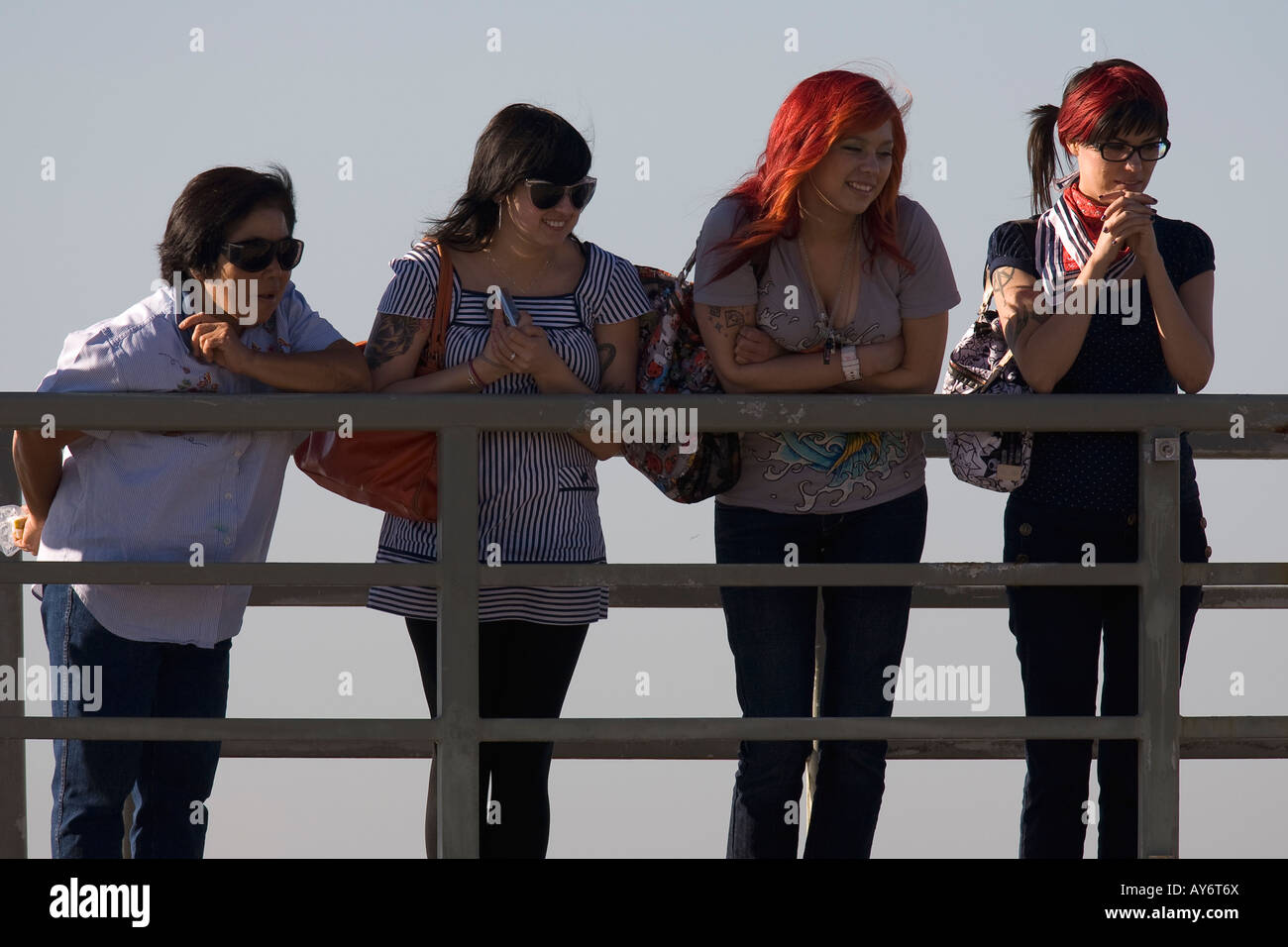 Four women standing at a rail looking at something Stock Photo - Alamy