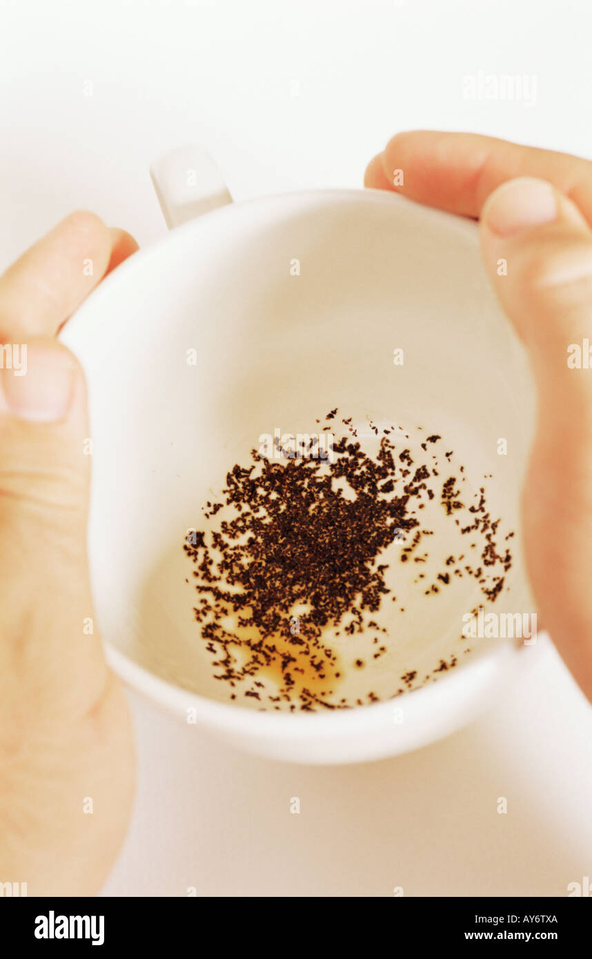 Two hands holding cup with tea leaves at bottom Stock Photo - Alamy