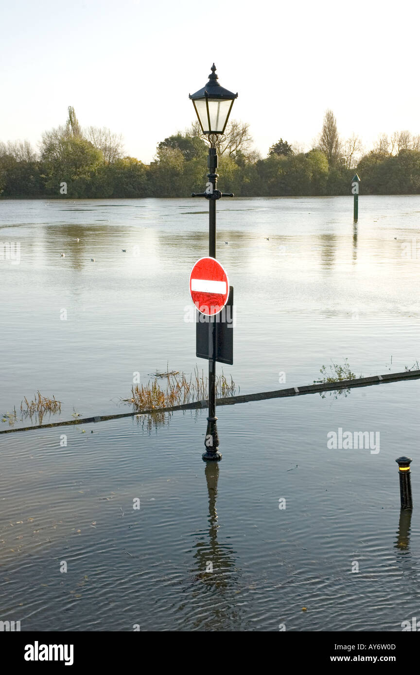 Spring tide floods riverside road. Lamp post with No Entry sign view ...