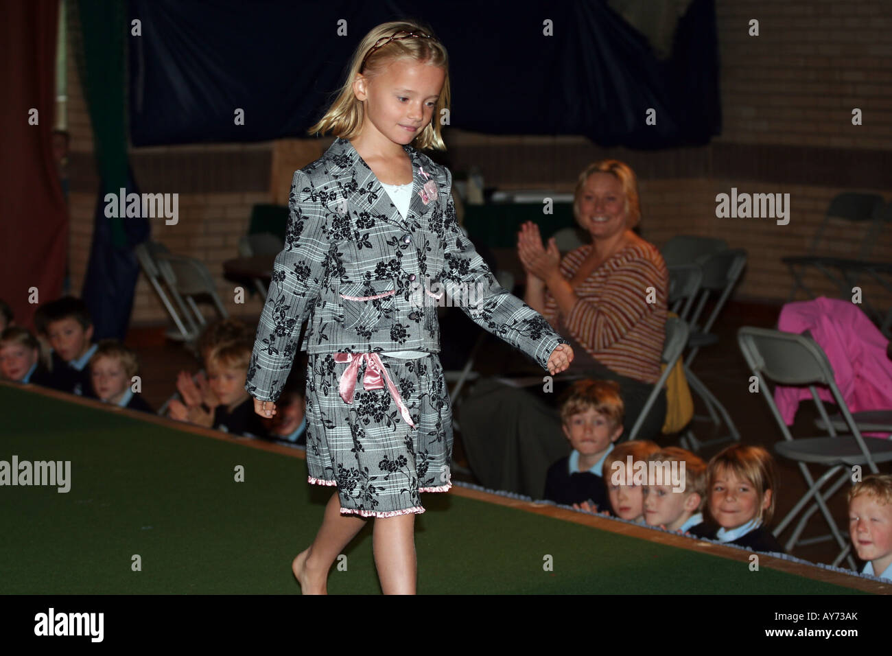 At a charity fashion show a young blonde model wears a grey suit Stock ...