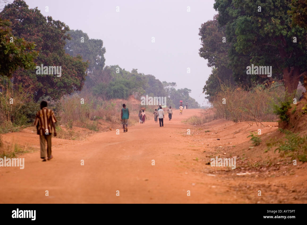 Villagers walking along a red dusty road to the next village in the ...