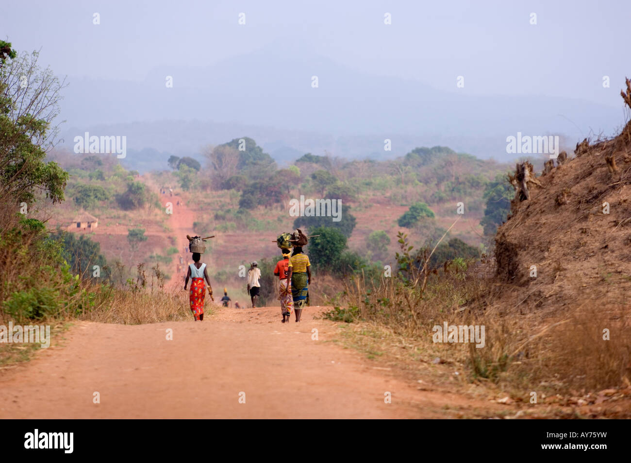 Villagers walking along a red dusty road to the next village in the ...