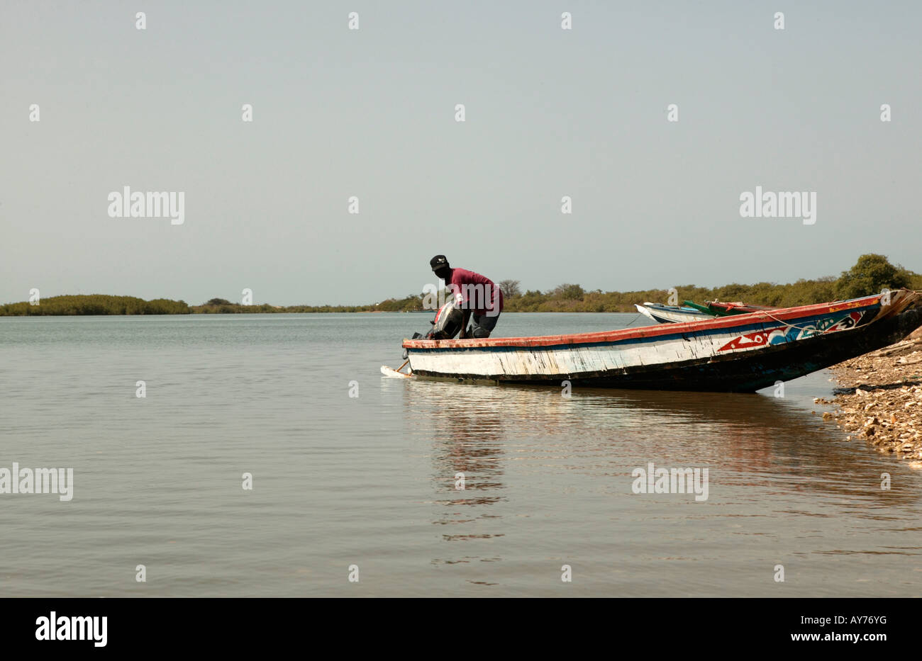 African man on boat, on the river border between The Gambia and Senegal ...