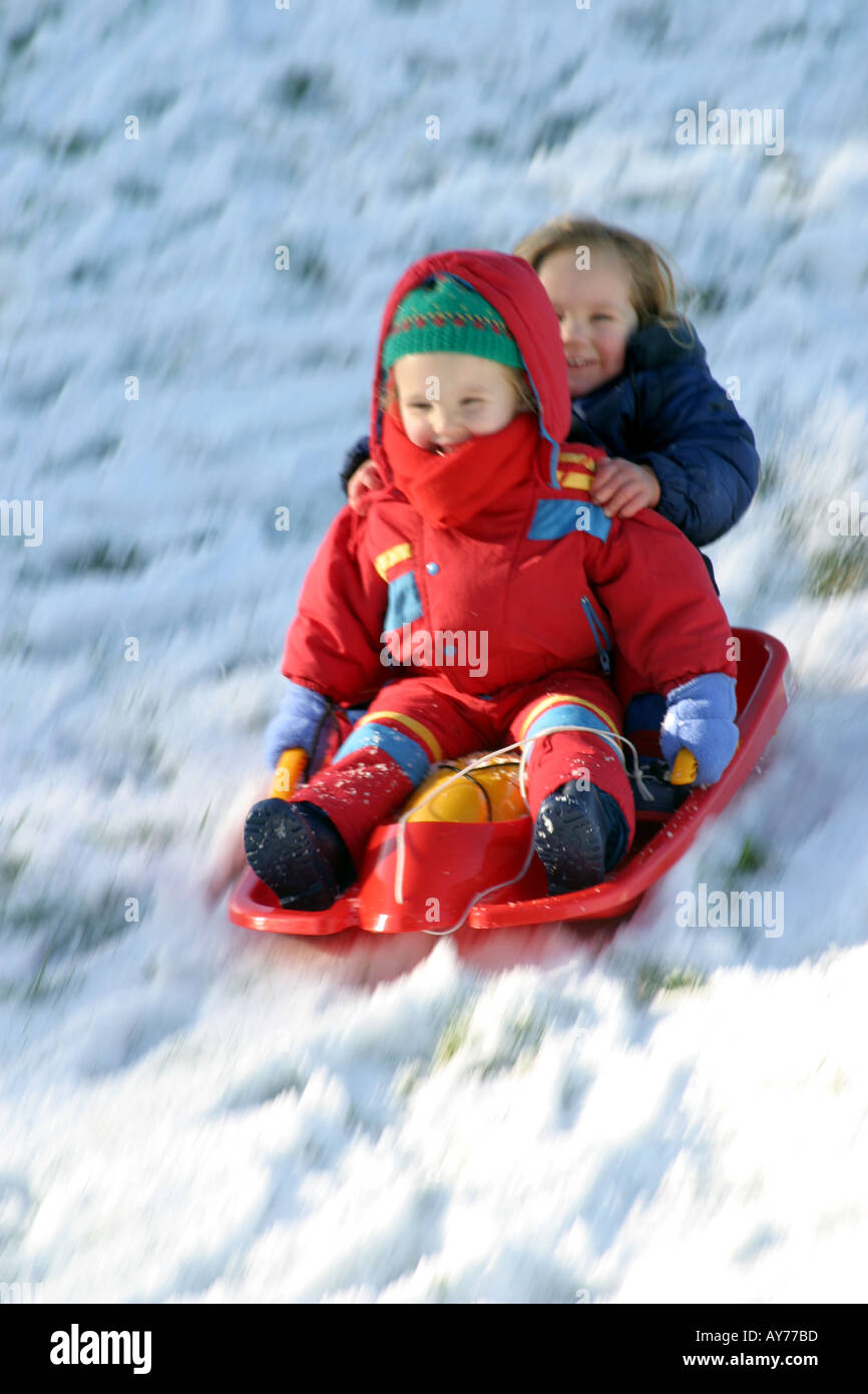 Two children playing on sledges hi-res stock photography and images - Alamy