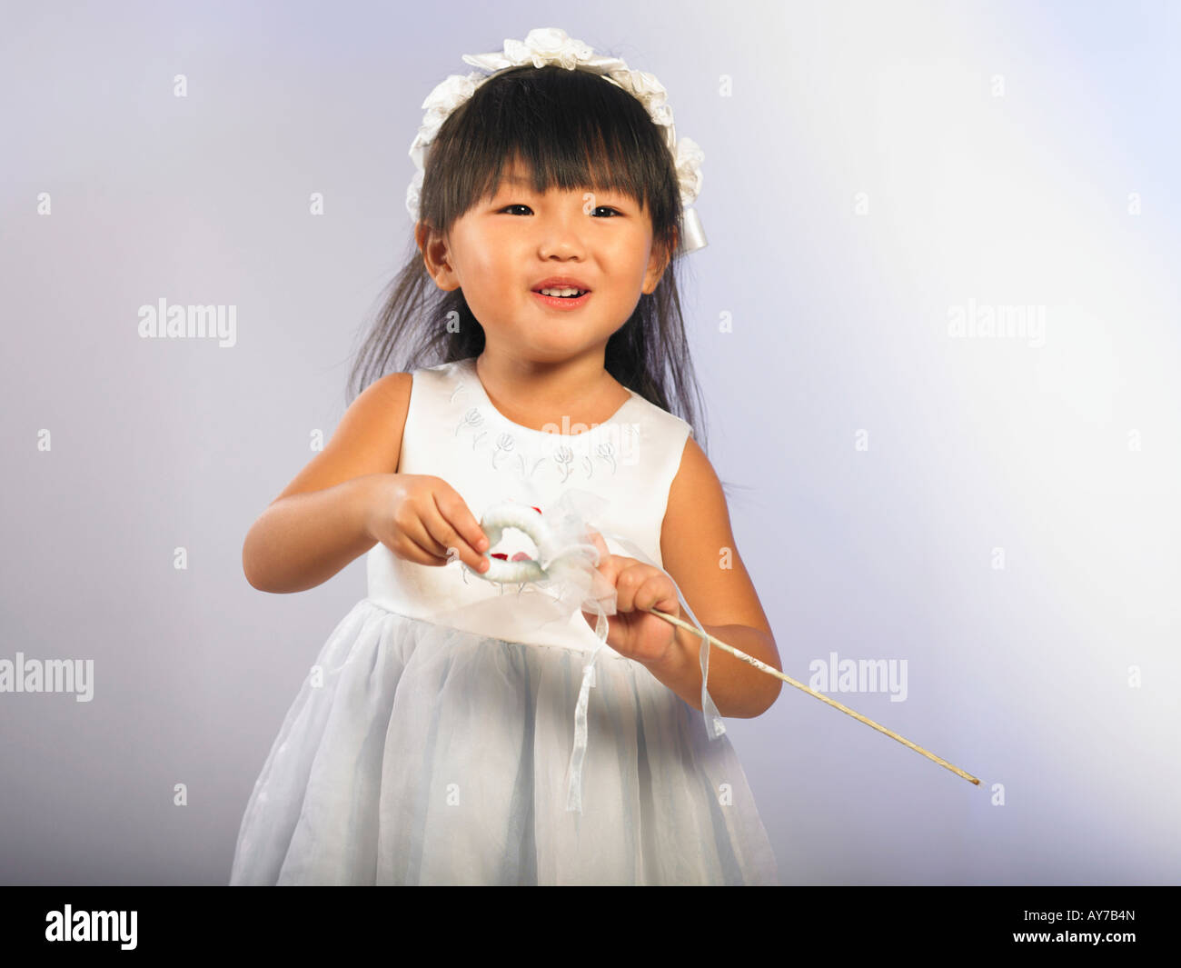 A little girl wearing white costume while holding a magic stick Stock ...