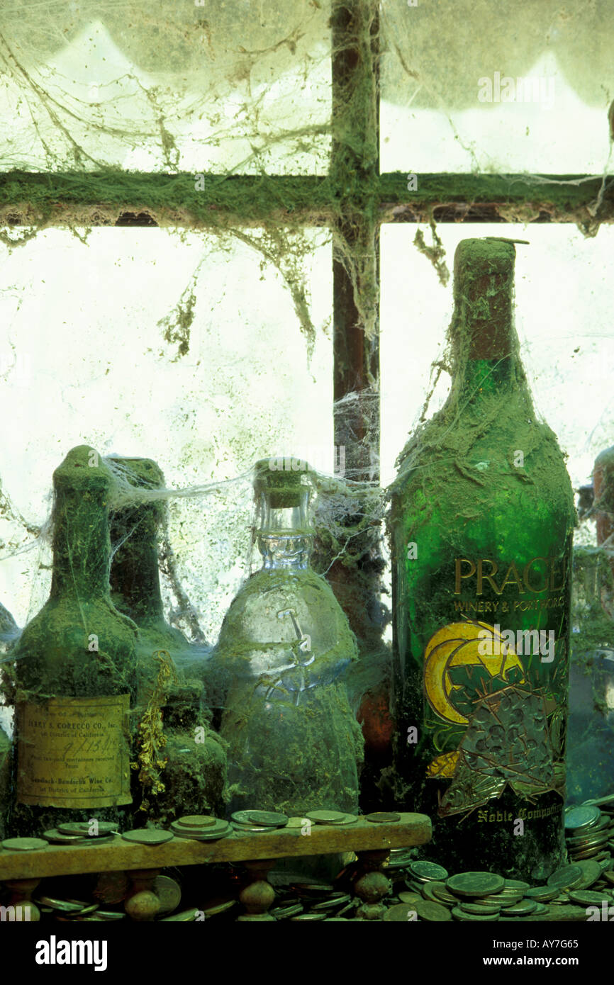 old dusty bottles and coins in dirty window with cob webs and dirt ...