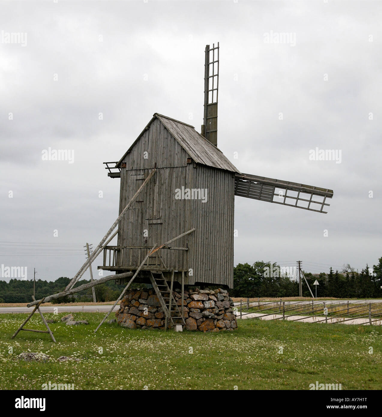 Windmill with rock filled base in a grass pasture cloudy day Stock ...