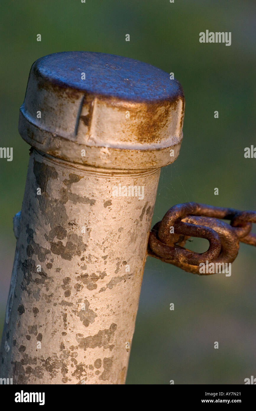 Metal post with chain against green background Stock Photo - Alamy