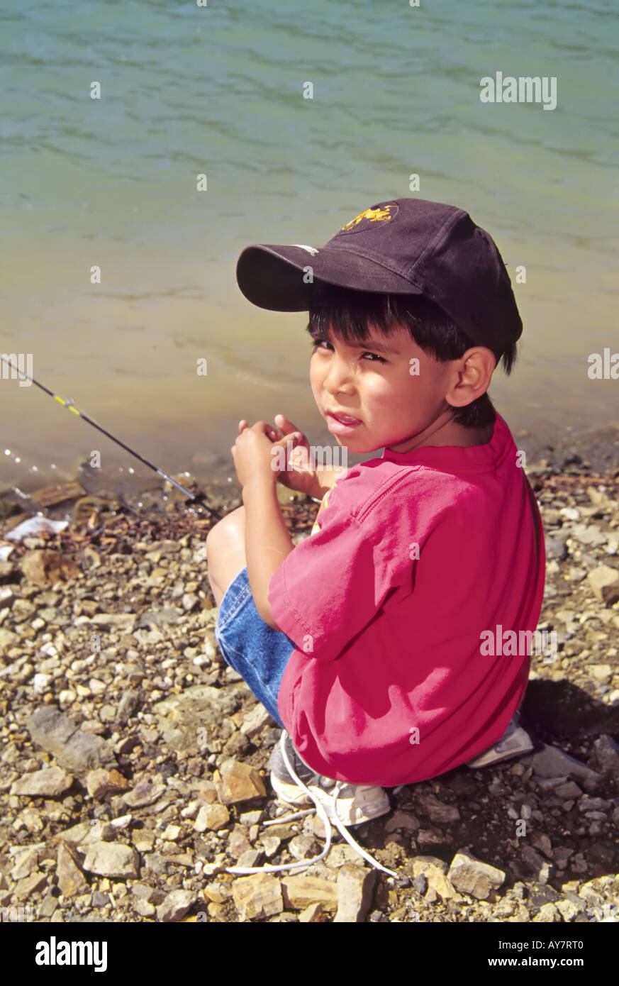 A young boy waits patiently with his rod and reel, trying to catch ...