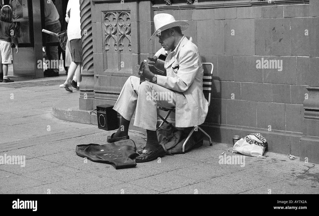 Middle aged colored man busking in the street with a guitar in ...