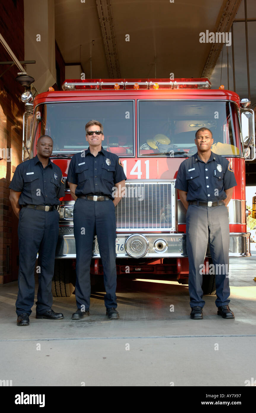 Portrait of three firefighters standing in front of firetruck Stock ...