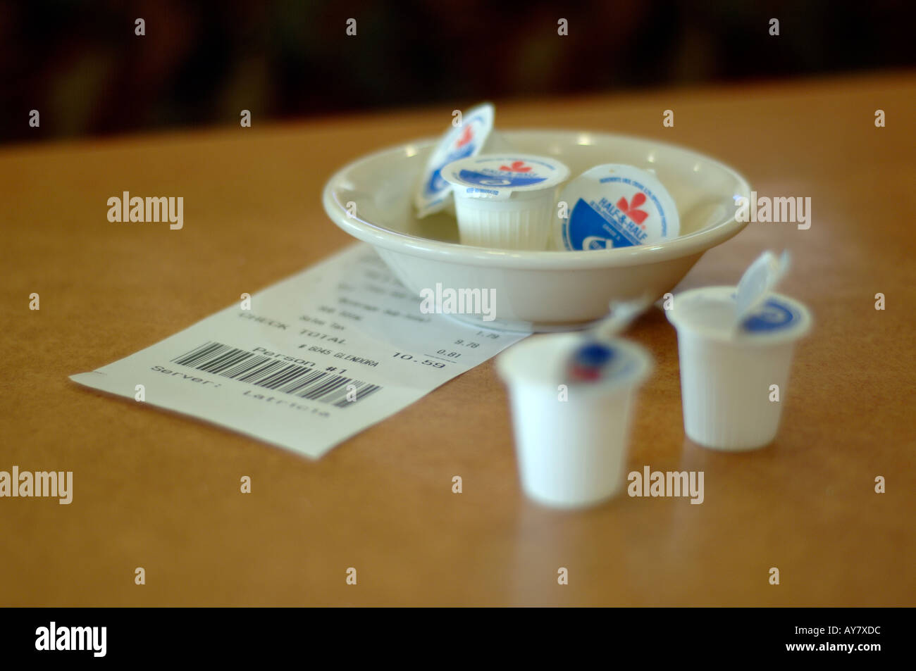 Empty cream containers and restaurant check on table Stock Photo - Alamy