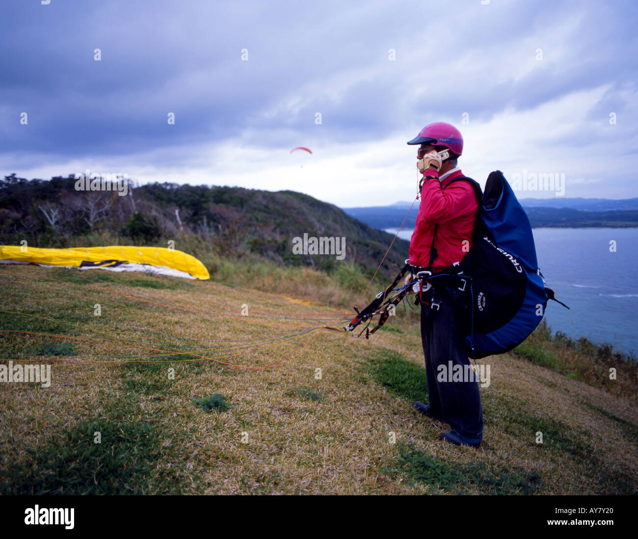 Elderly Japanese man takes a call before he paraglides from Teniya Cape ...