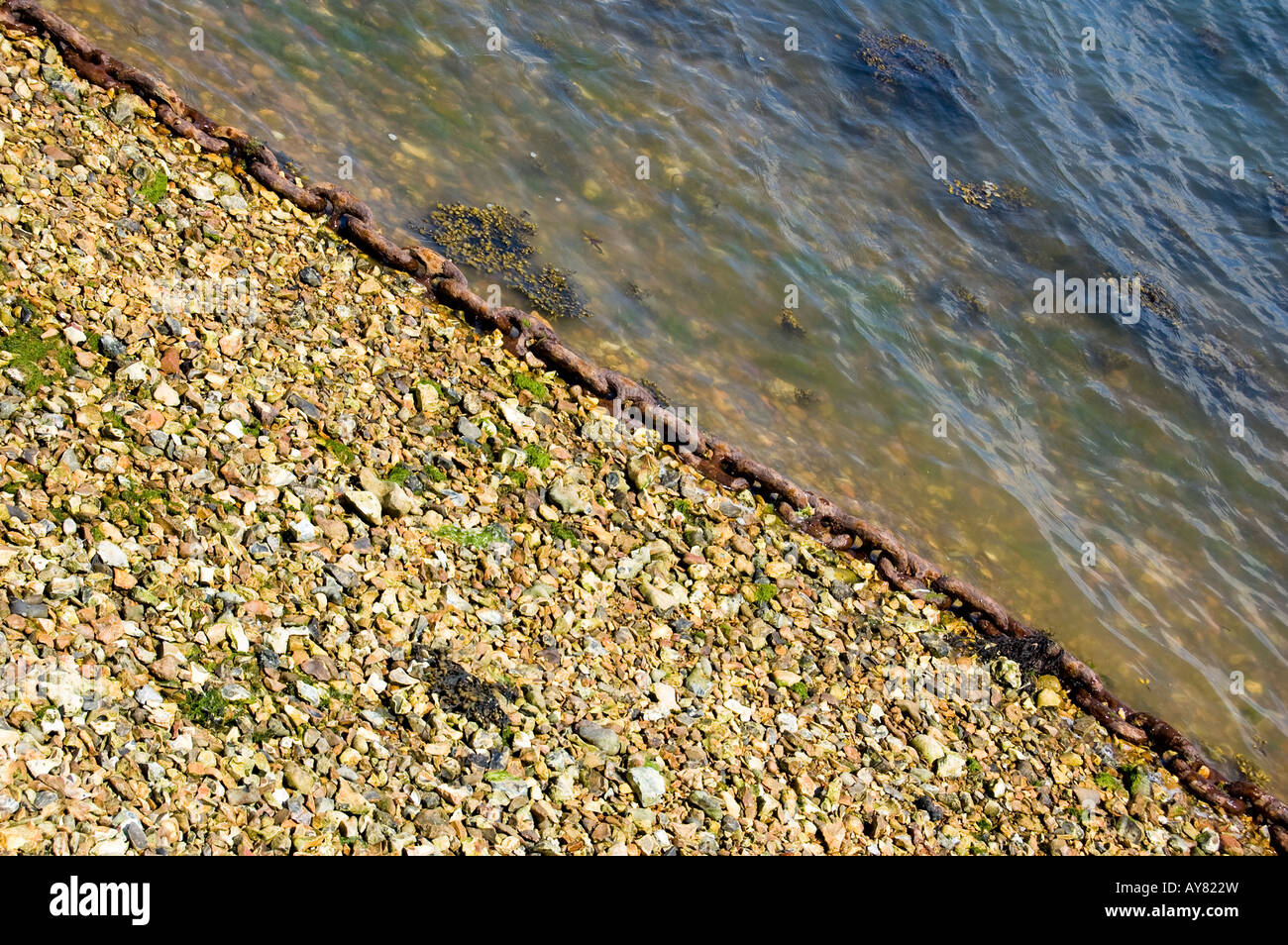A chain on a beach at tide level, acting as a dividing line between sea ...