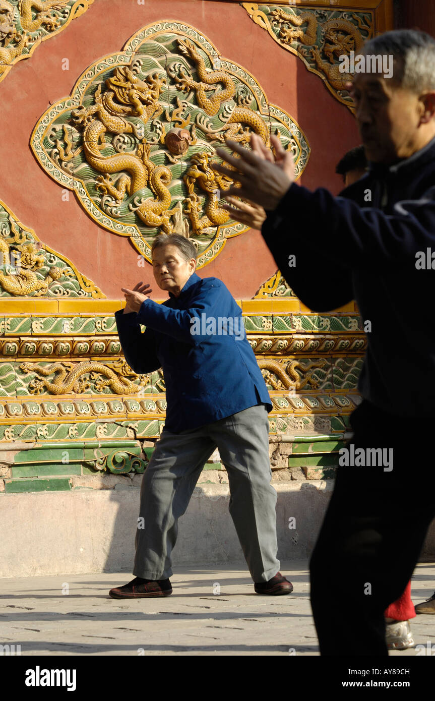 Chinese elder people practice Tai Chi in front of a traditional wall in ...