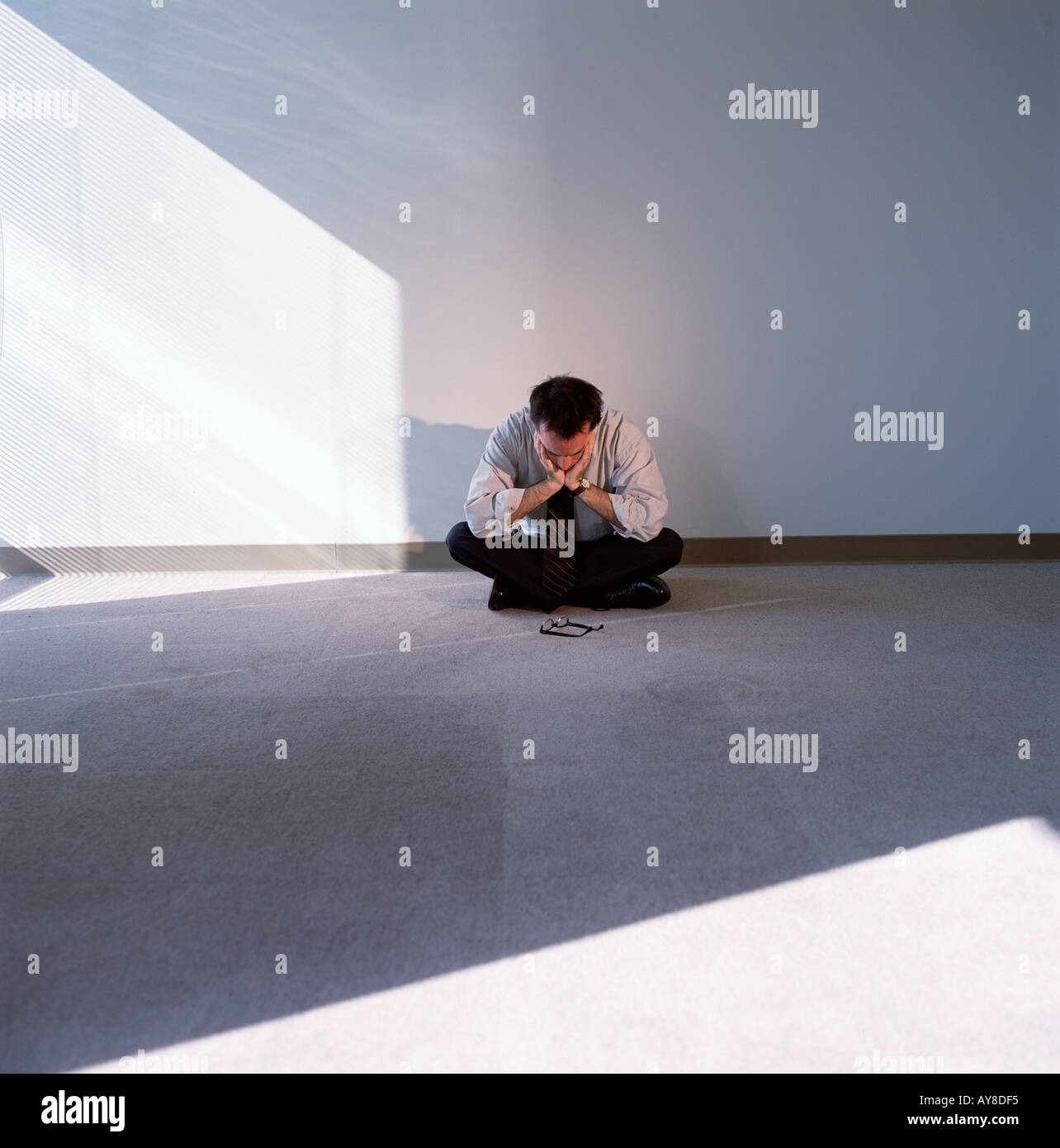 Depressed office employee sits in empty space in highrise office ...