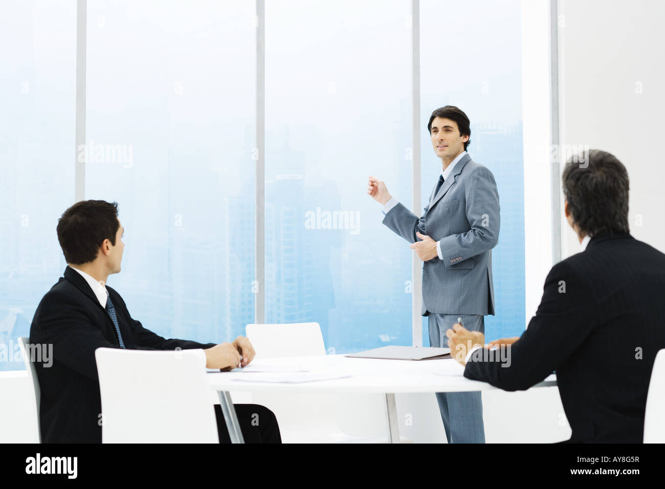 Businessmen in meeting, one standing, pointing out window Stock Photo ...