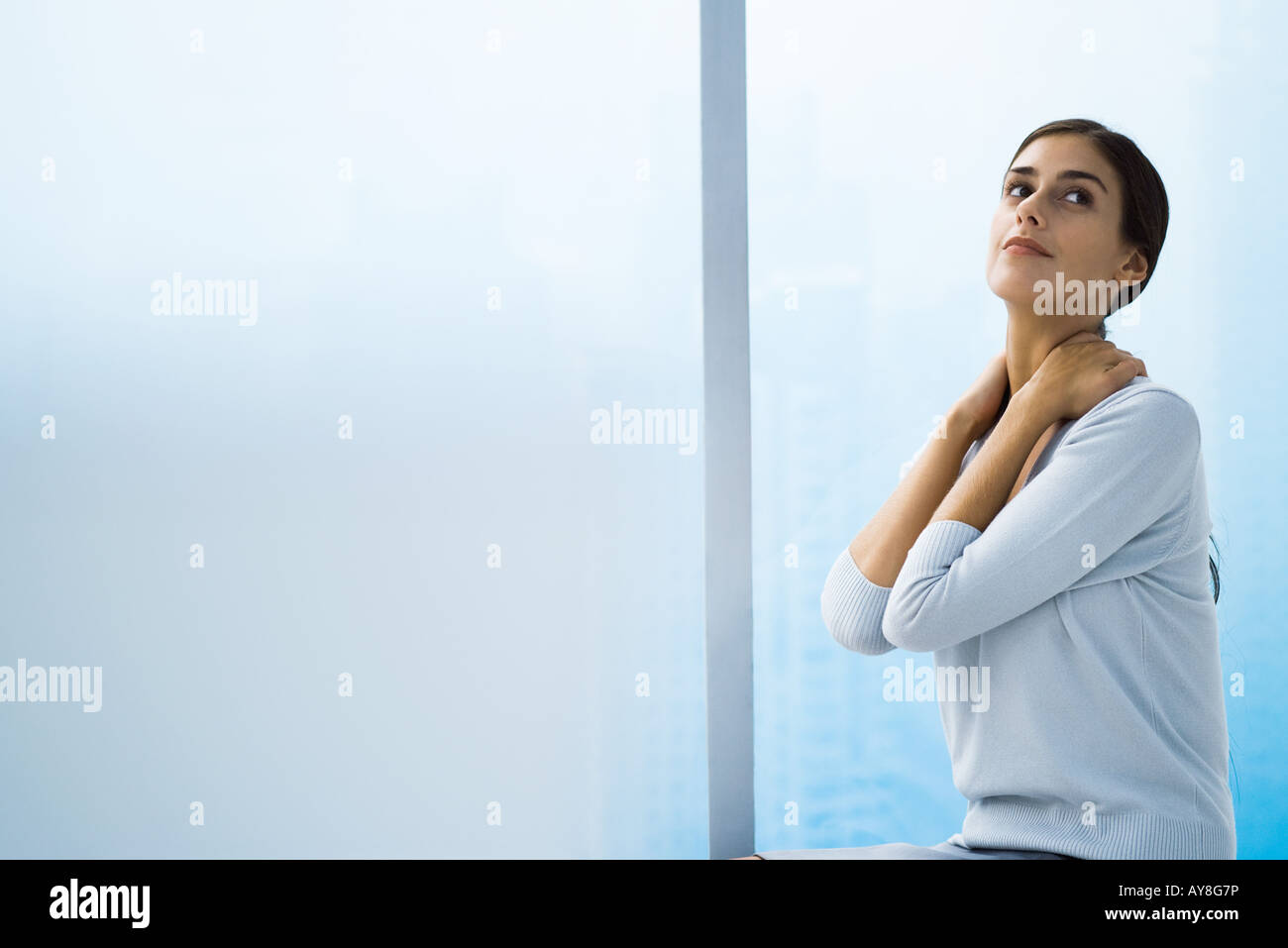 Woman with hands behind neck, looking up Stock Photo - Alamy