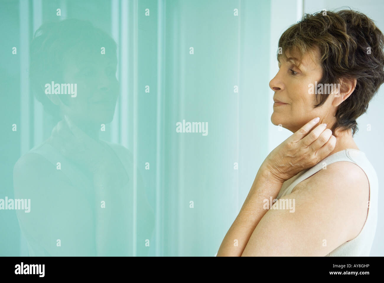 Woman looking at her reflection in window, side view Stock Photo - Alamy