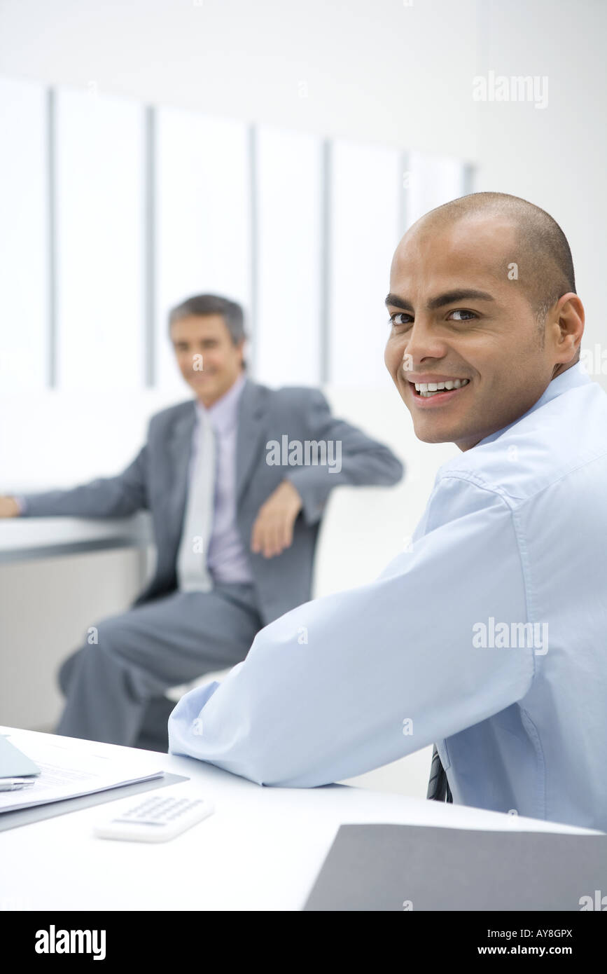 Two businessmen sitting in office, smiling at camera Stock Photo - Alamy