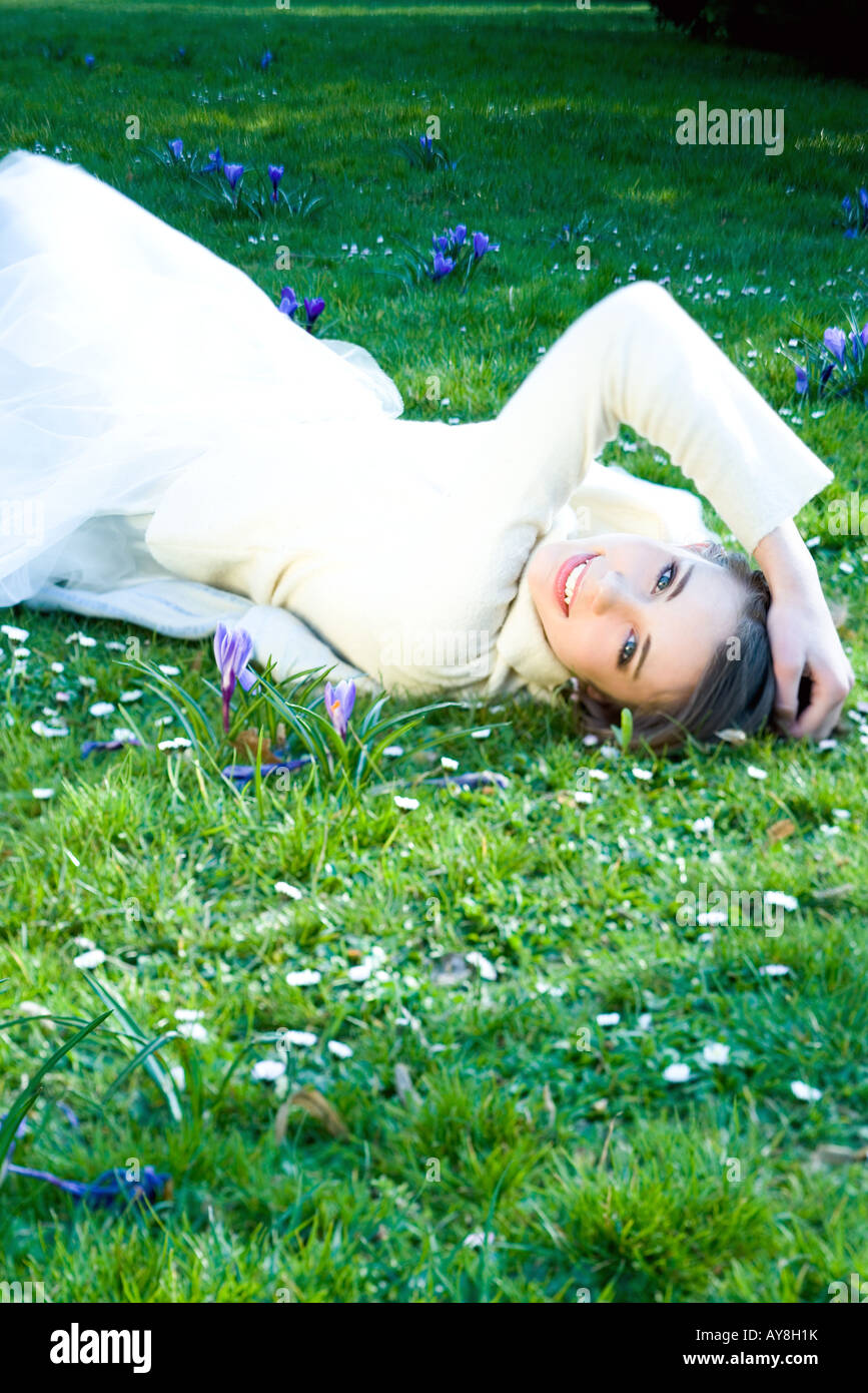 Teenage girl lying on the ground with hand on head, smiling at camera ...
