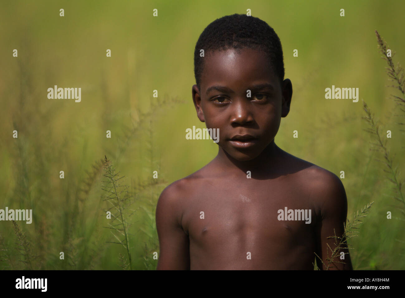 A young African boy standing in a field of green grass Stock Photo - Alamy