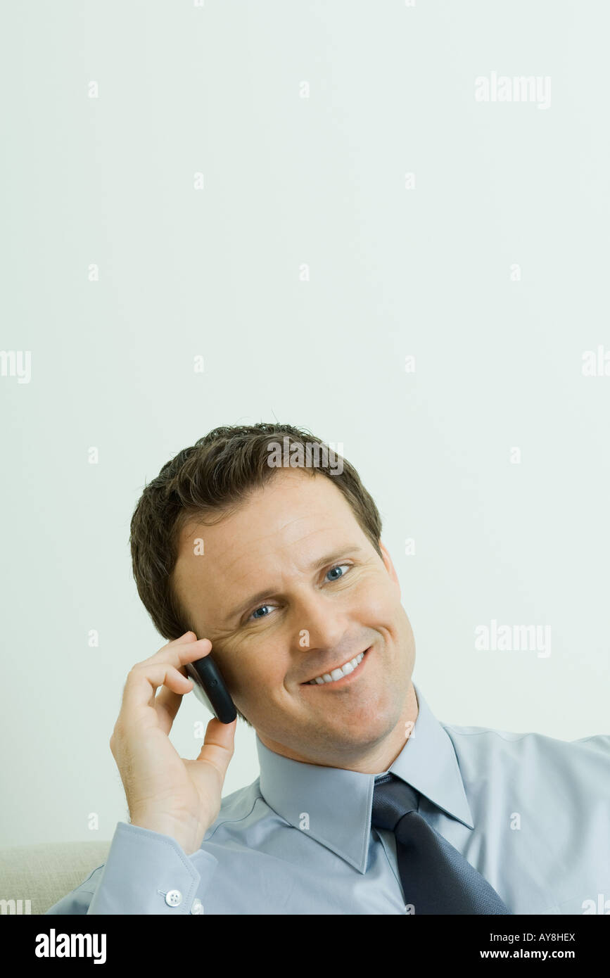 Businessman using cell phone, head tilted, smiling at camera Stock ...