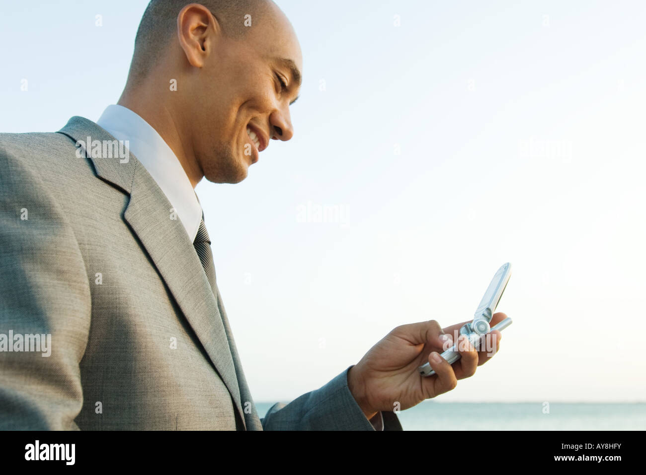 Businessman looking down at cell phone outdoors, side view, low angle ...