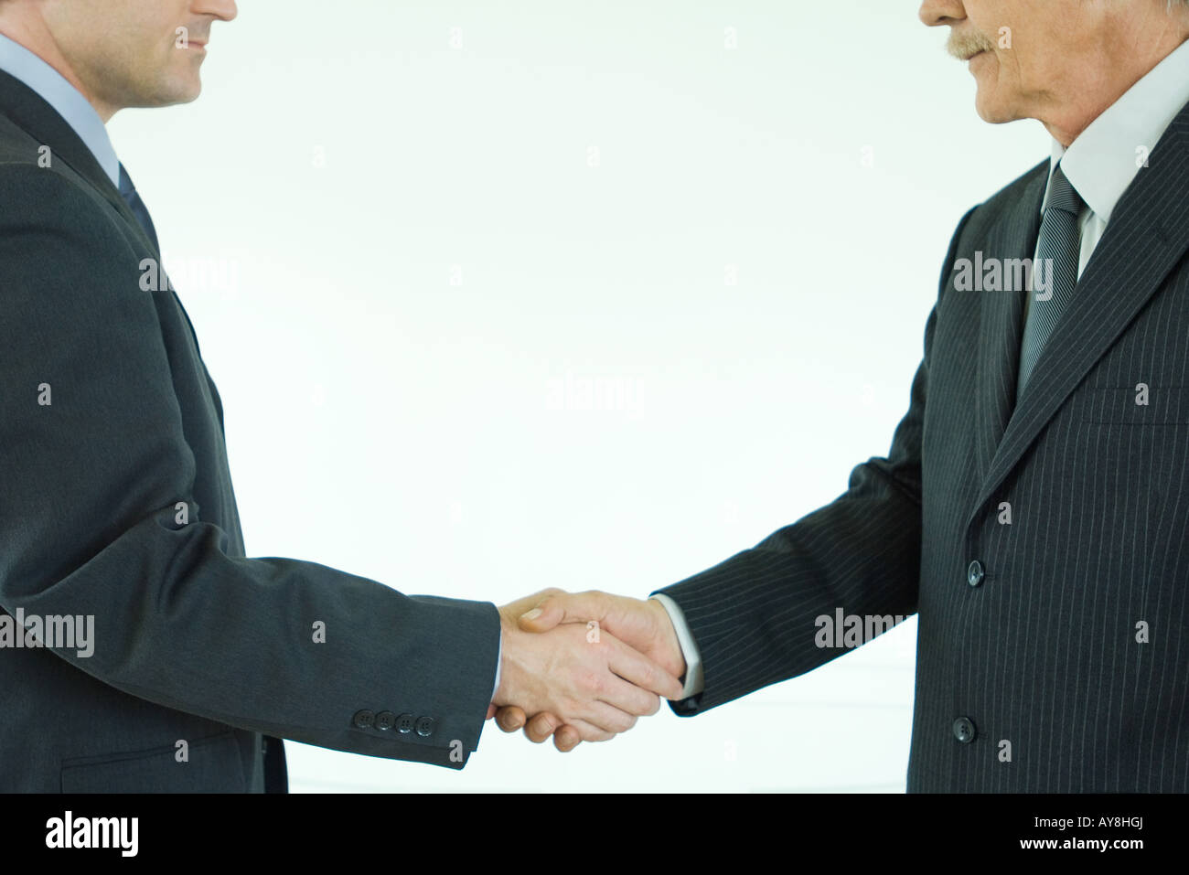 Two businessmen shaking hands, cropped side view Stock Photo - Alamy