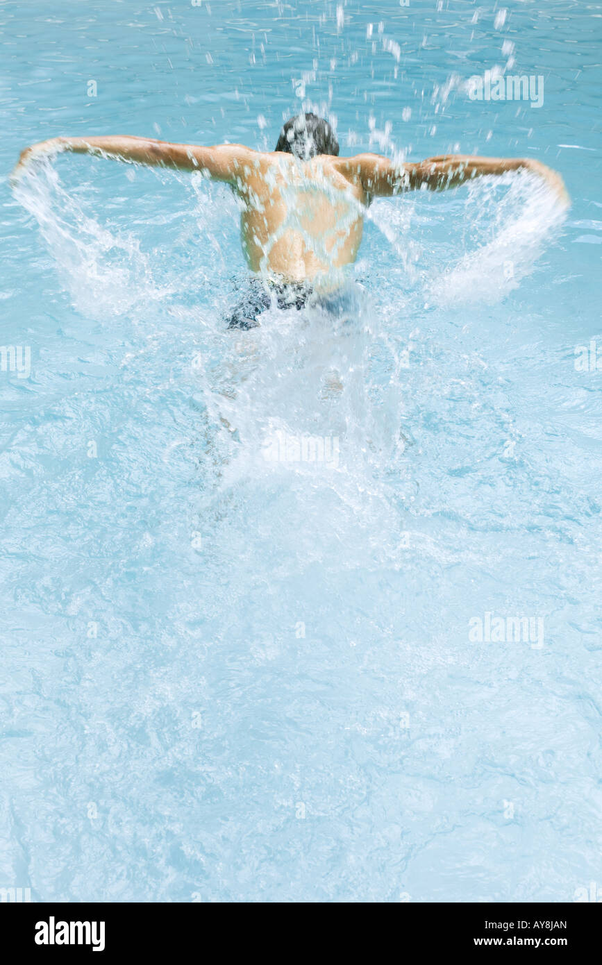 Man swimming and splashing in pool, rear view Stock Photo - Alamy