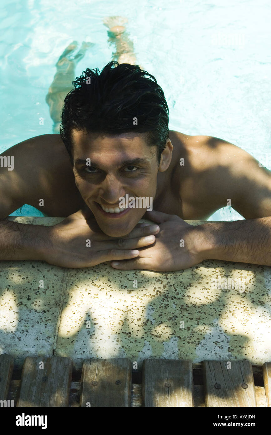 Man in swimming pool, leaning against side with head resting on arms ...