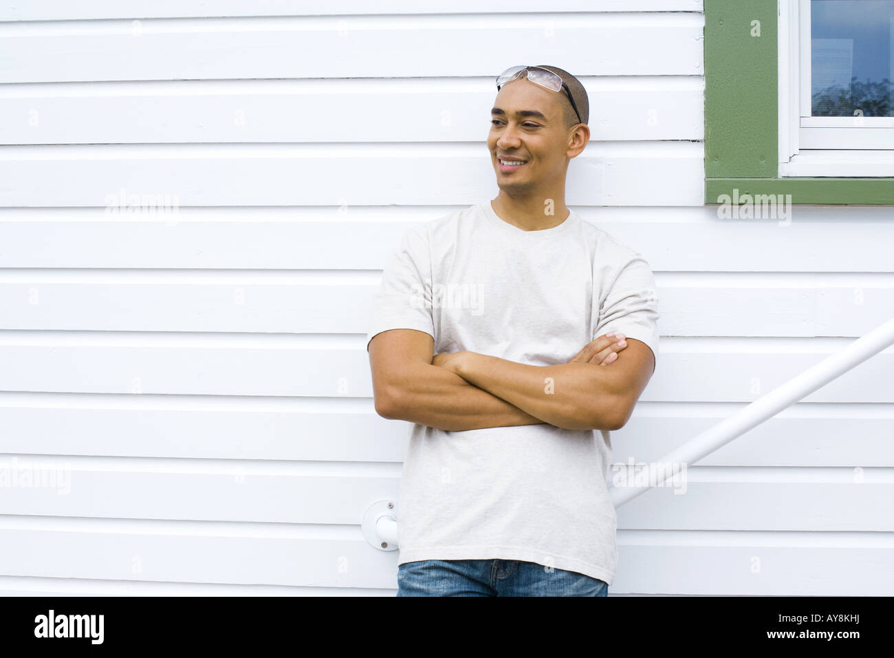 Man leaning against side of house, arms folded, smiling Stock Photo - Alamy