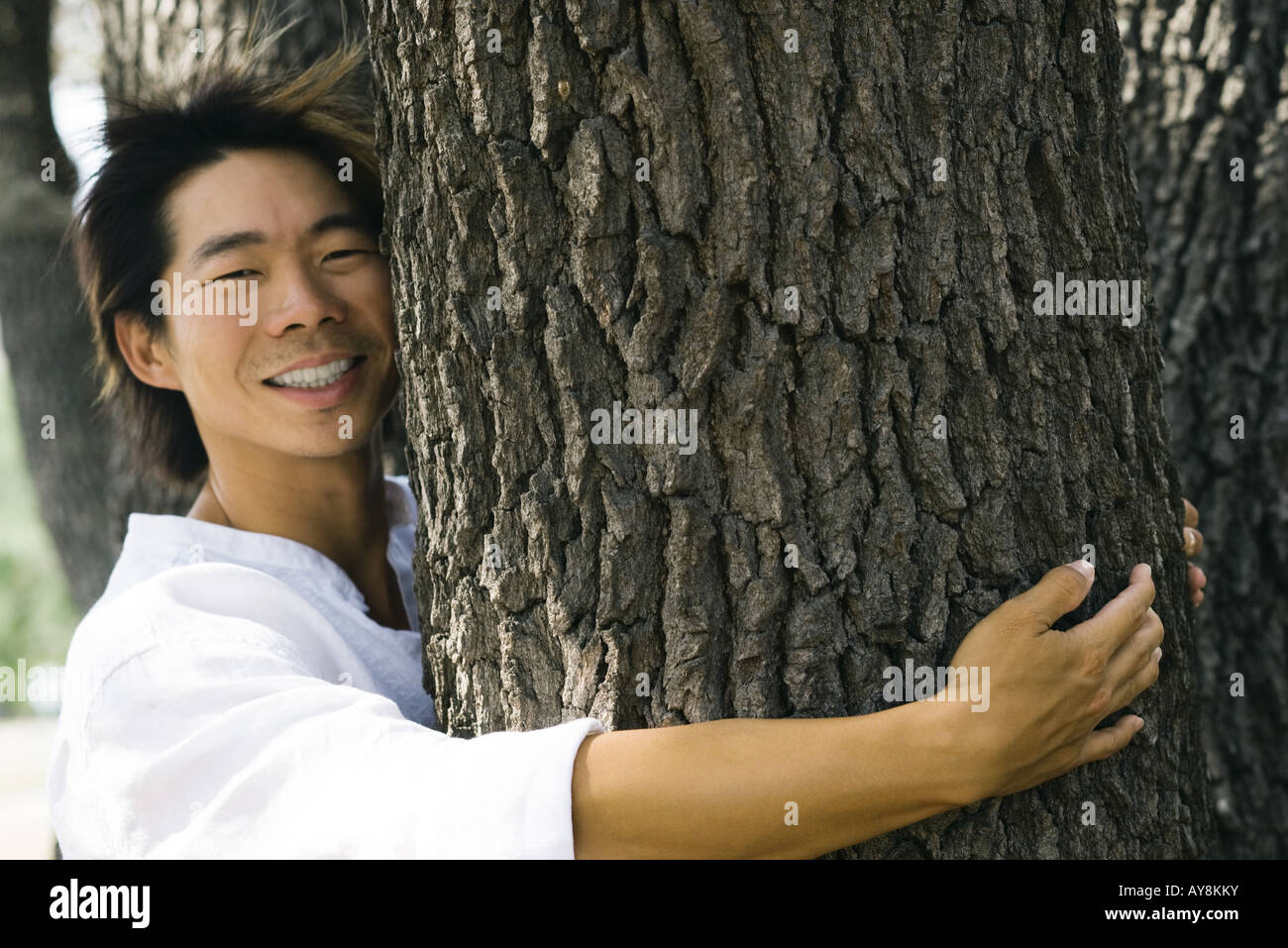 Man hugging tree trunk, smiling at camera Stock Photo - Alamy