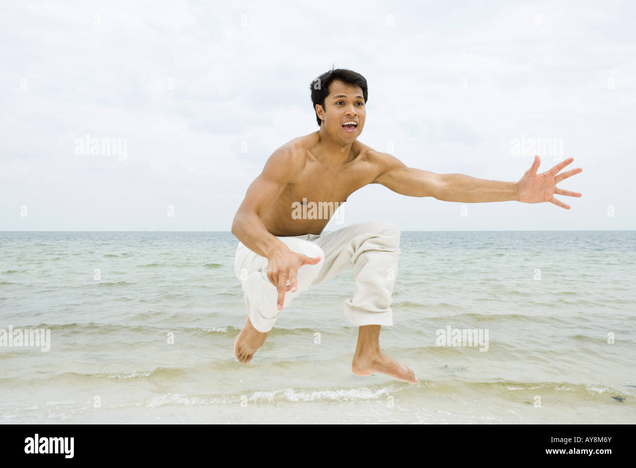 Man jumping in the air and shouting, ocean in background Stock Photo ...