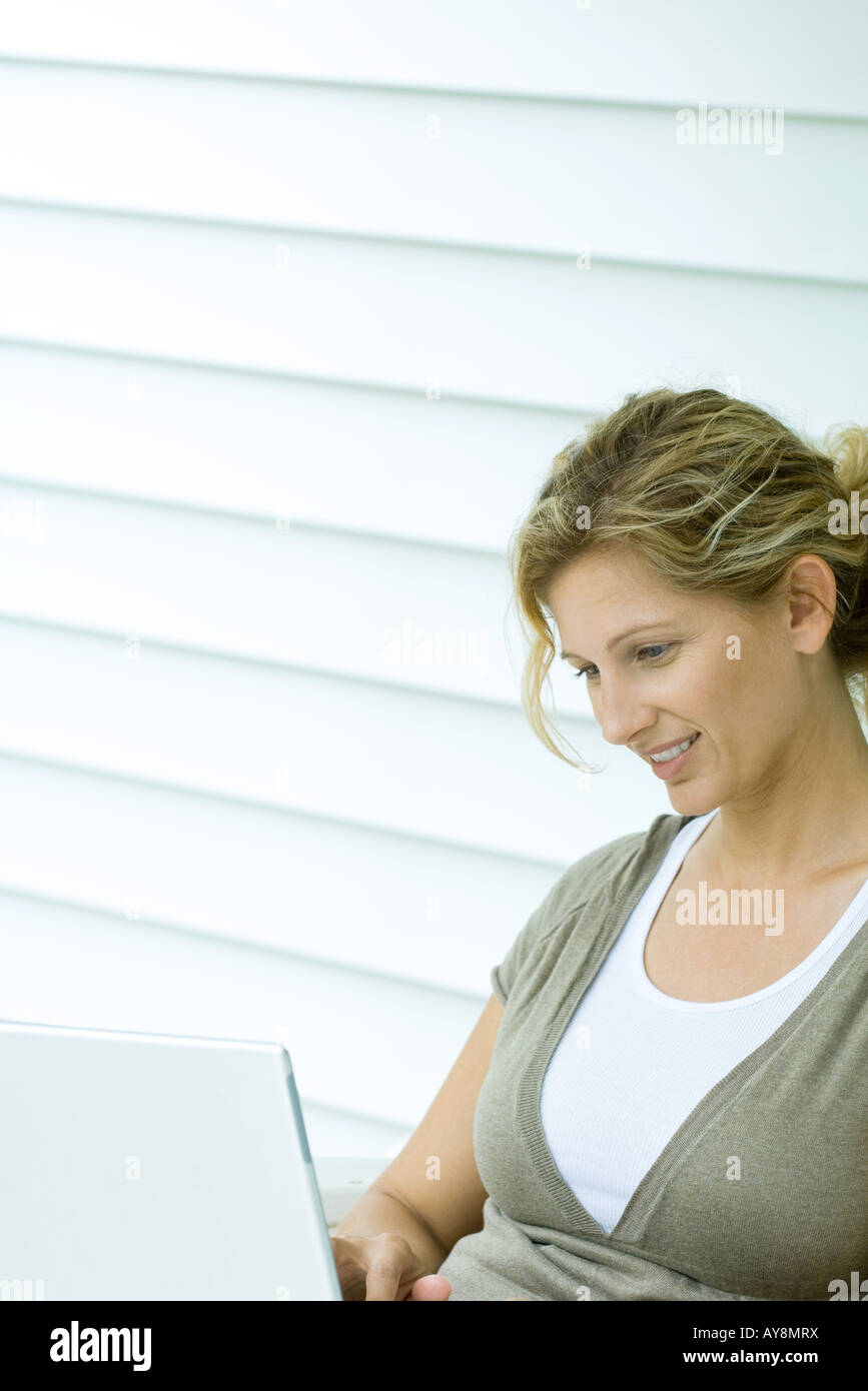 Woman looking down at laptop computer, smiling, cropped Stock Photo - Alamy