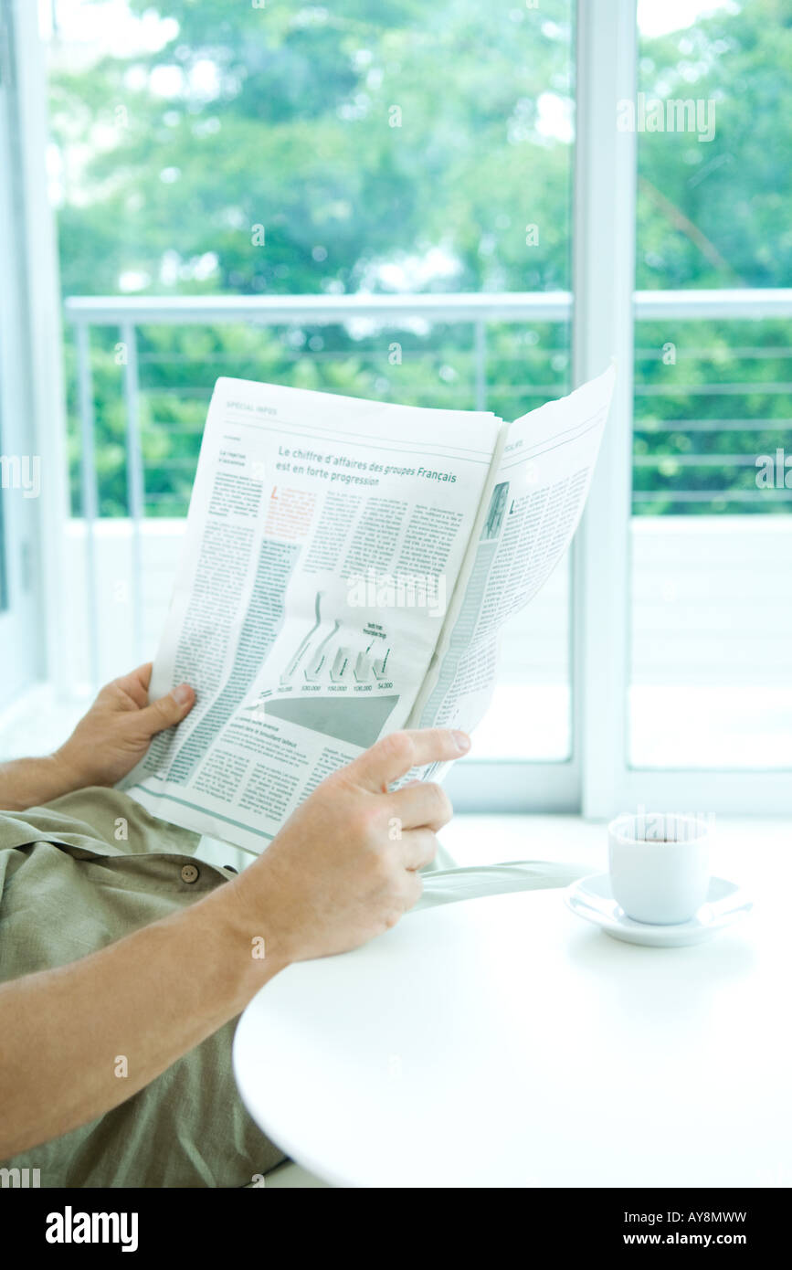Man reading newspaper at table, cropped view Stock Photo - Alamy