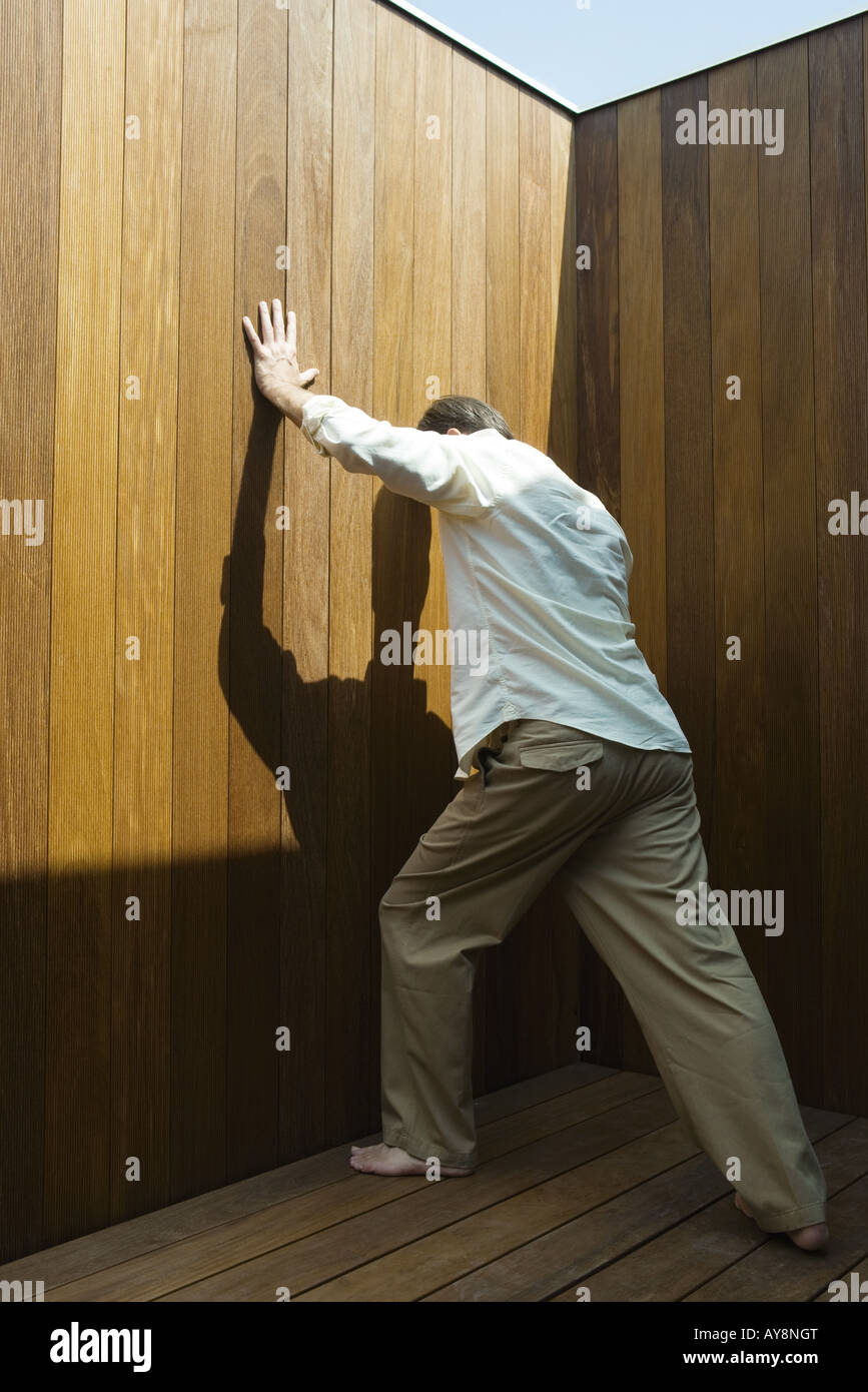 Man standing, pushing against wood paneling, side view Stock Photo - Alamy