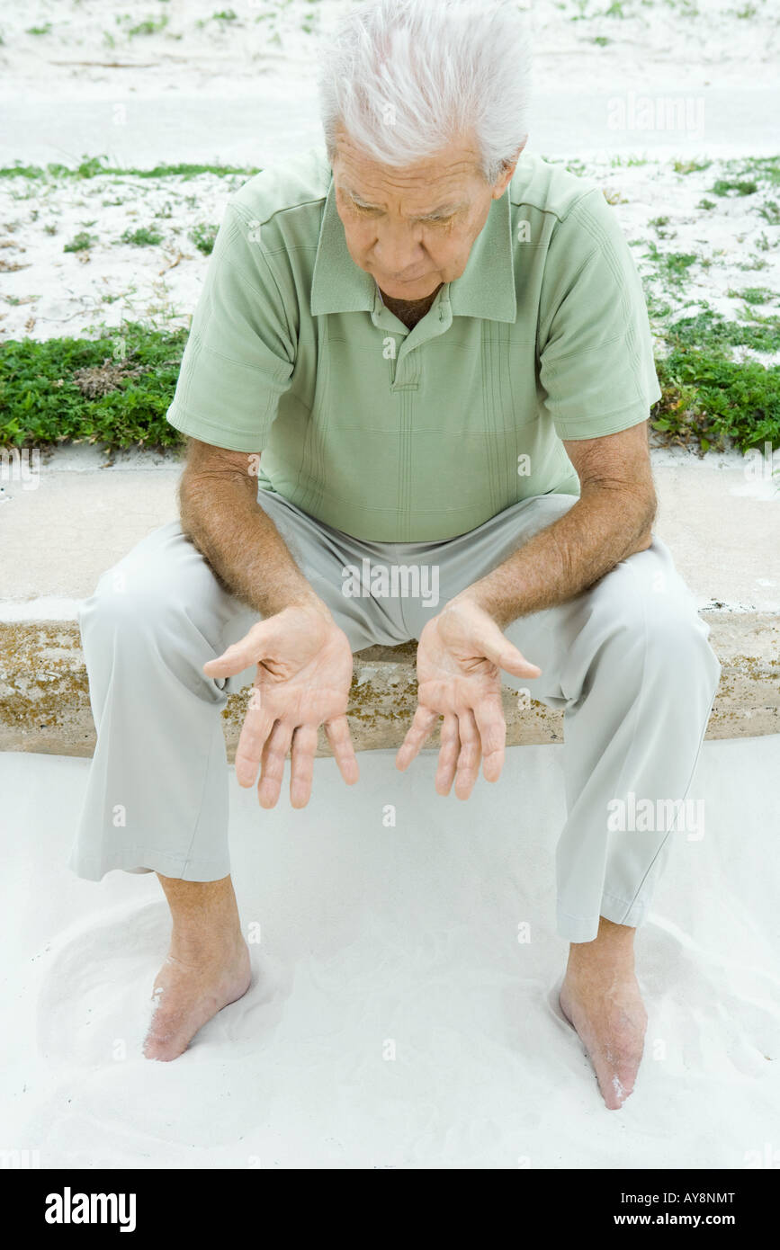 Man sitting at the beach, looking down at hands, high angle view Stock ...
