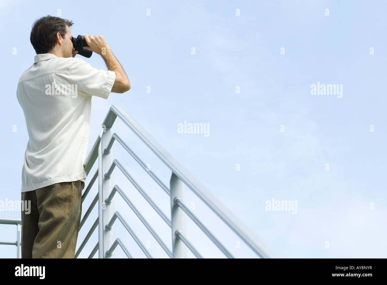 Man leaning against railing, looking through binoculars Stock Photo - Alamy
