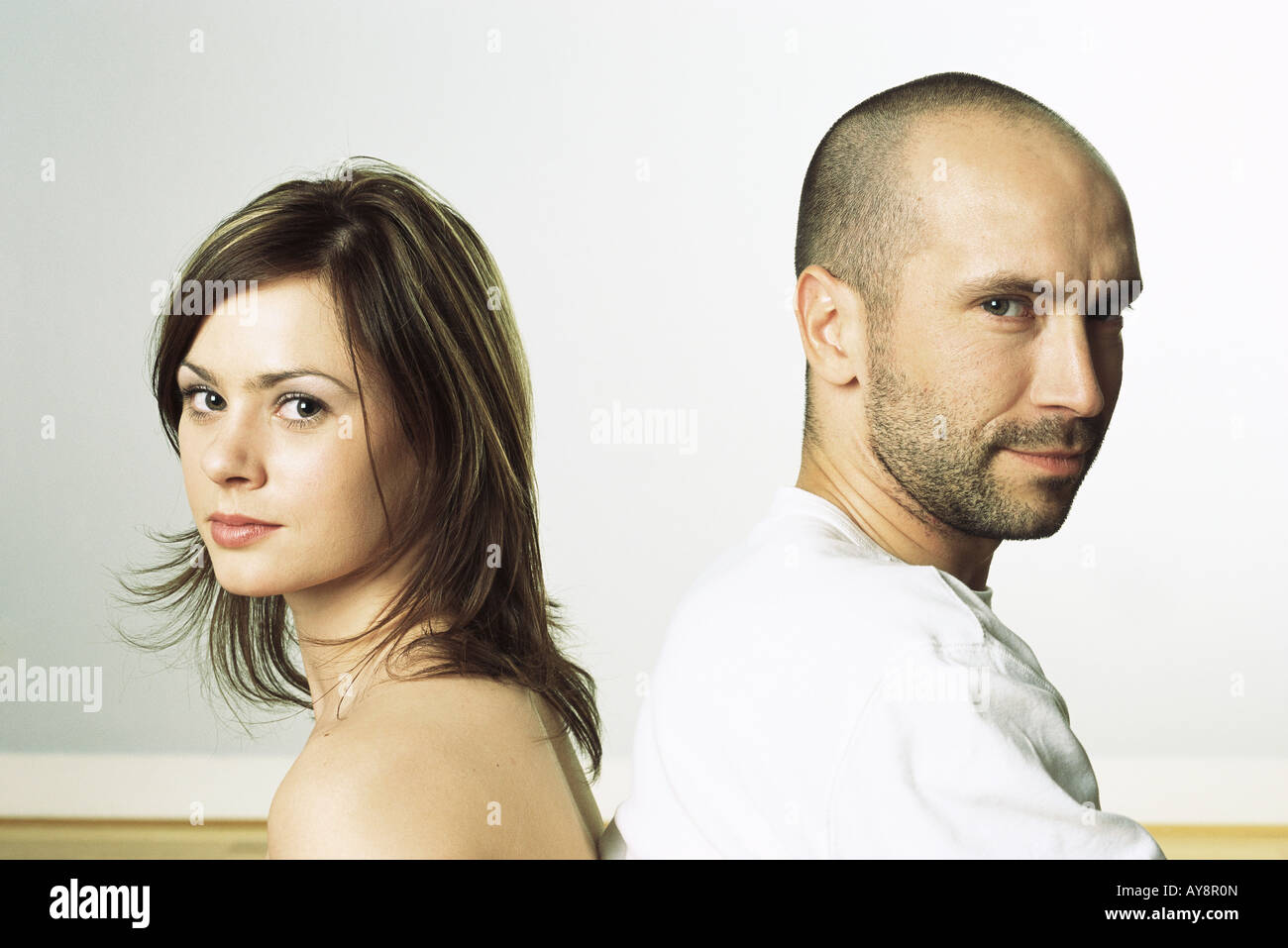 Couple back to back, both looking over shoulders at camera Stock Photo ...