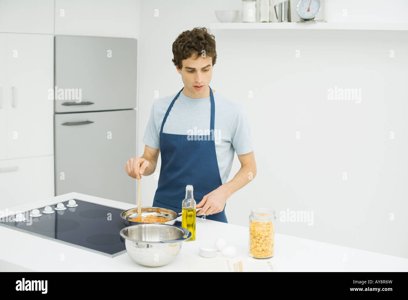 Man standing at stove, cooking, looking down at recipe Stock Photo - Alamy