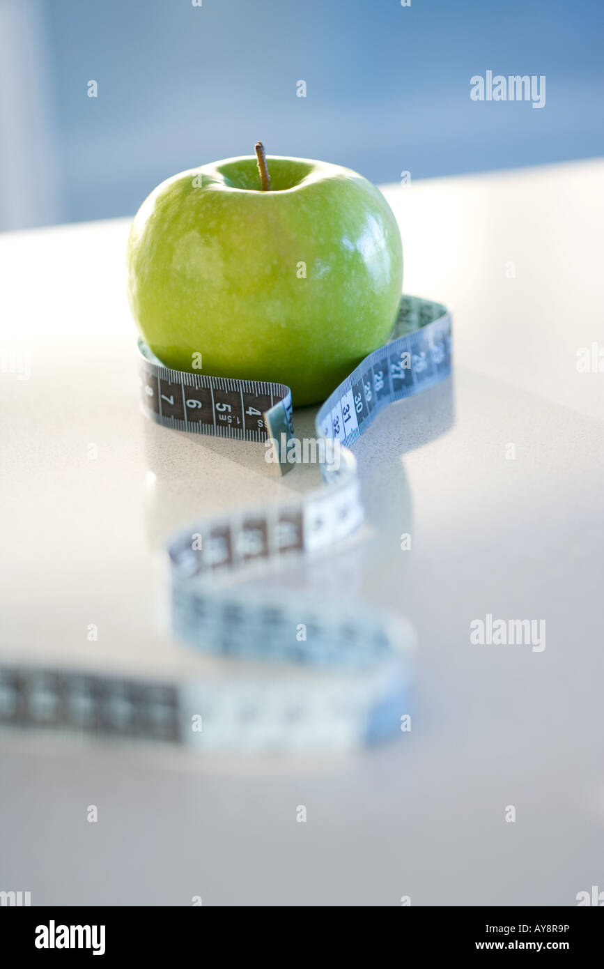 Measuring tape wrapped around green apple, close-up Stock Photo - Alamy
