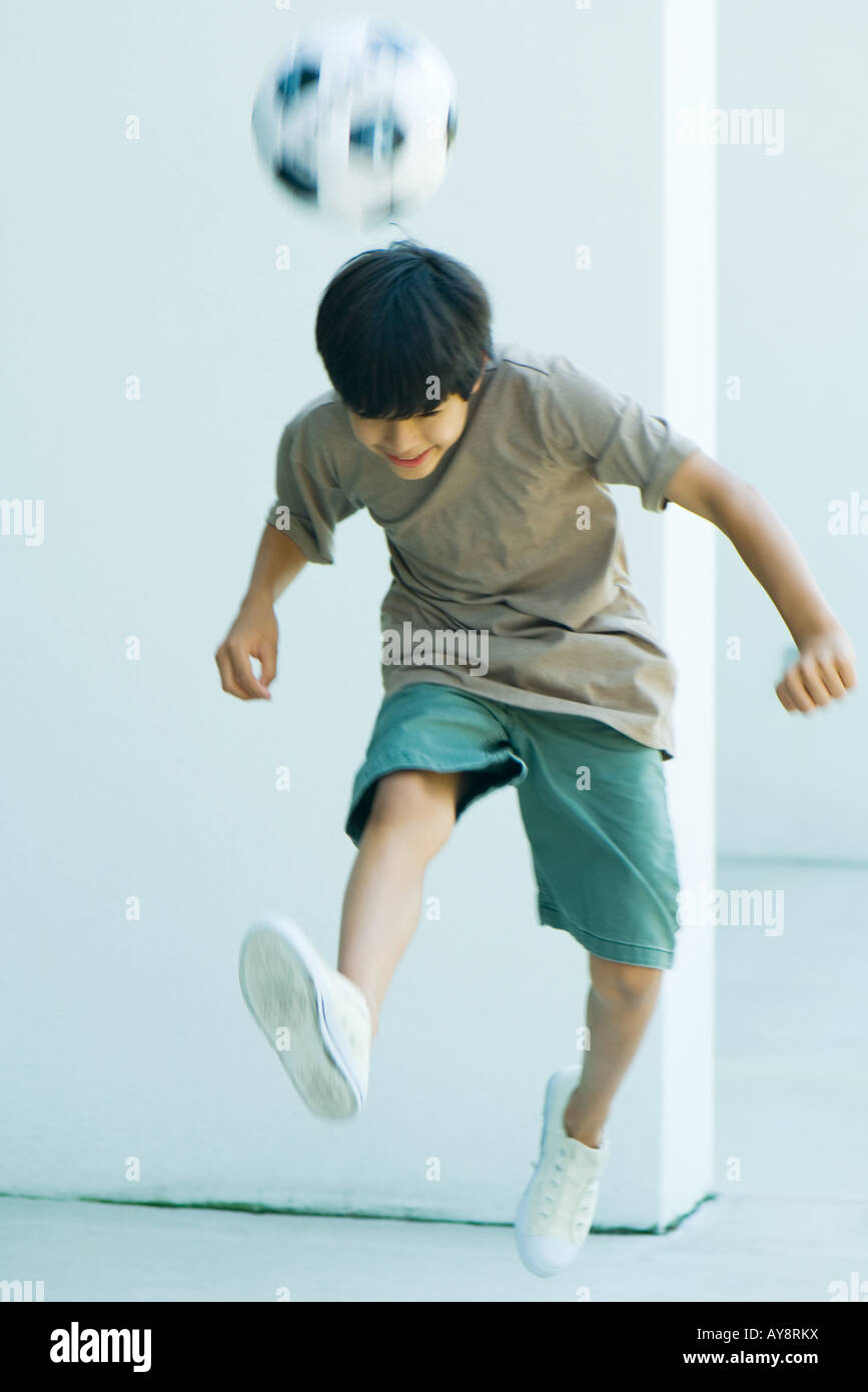 Little boy playing with soccer ball, jumping, head down Stock Photo - Alamy