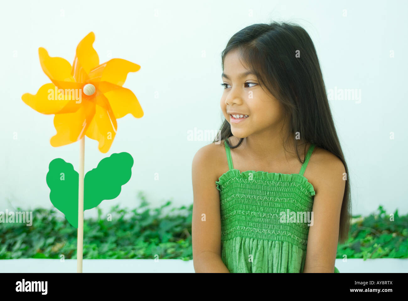 Little girl looking at flower-shaped pinwheel, smiling Stock Photo - Alamy