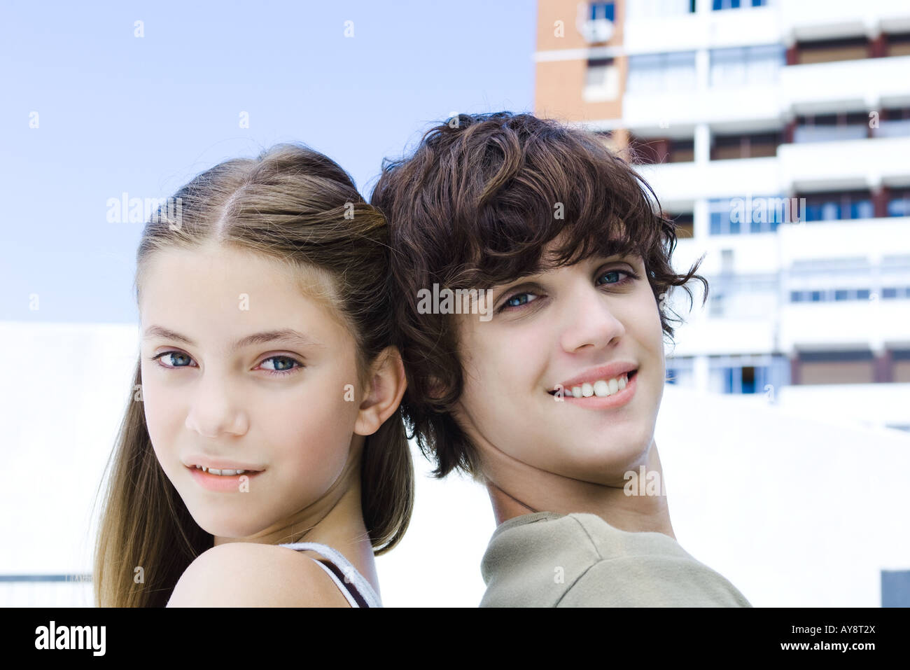 Two young friends back to back, smiling at camera, side view Stock ...