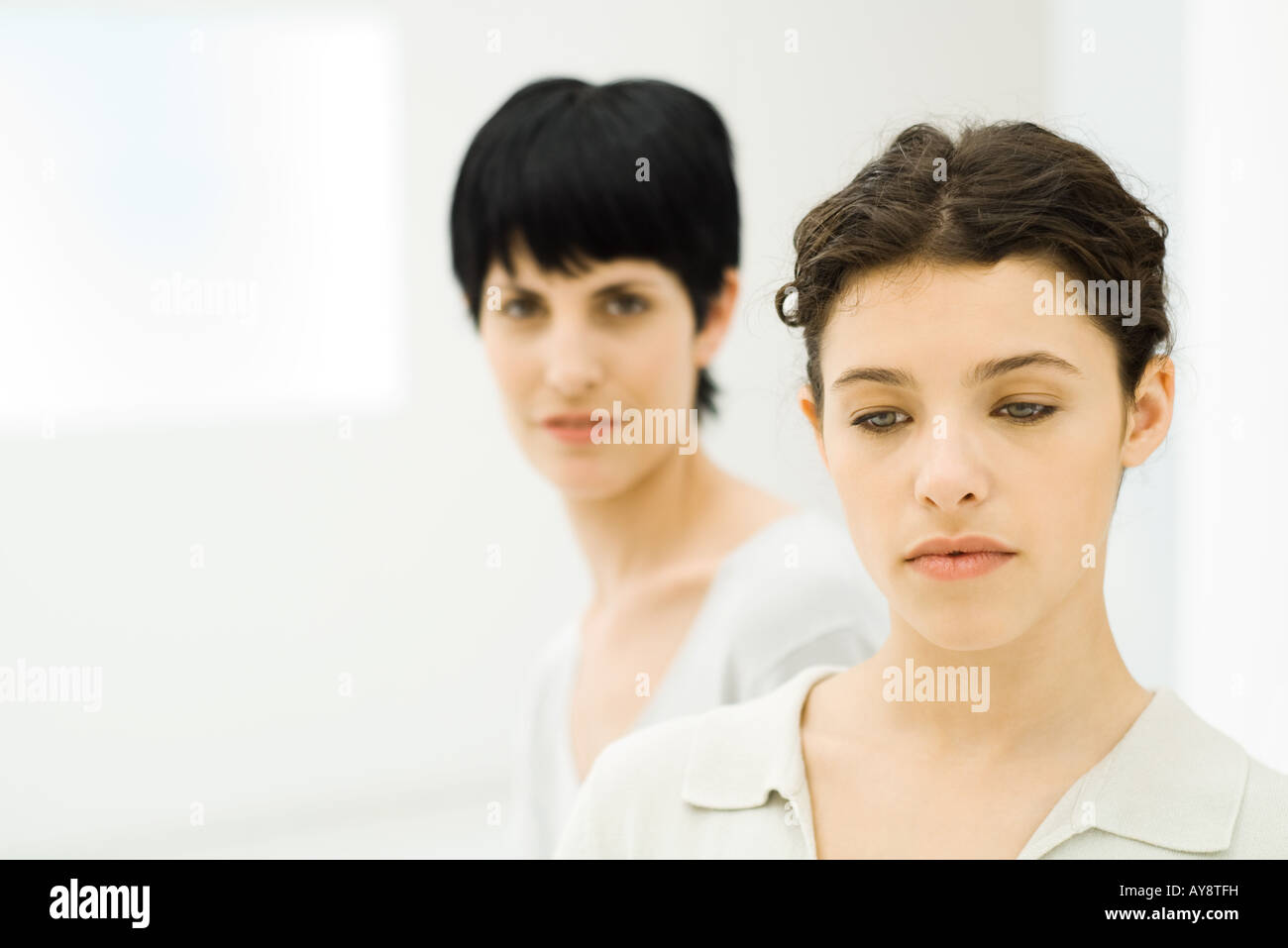 Young businesswoman looking down, colleague standing behind her ...